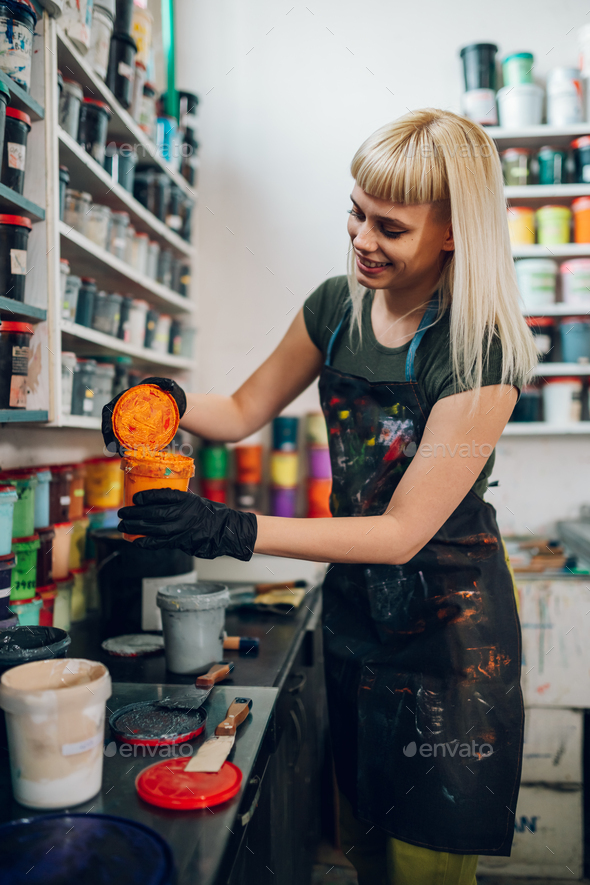 Smiling print shop worker opening plastisol ink bucket and choosing ...