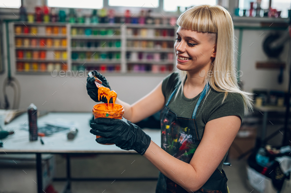 Smiling print shop worker mixing silkscreen printing ink with spatula ...