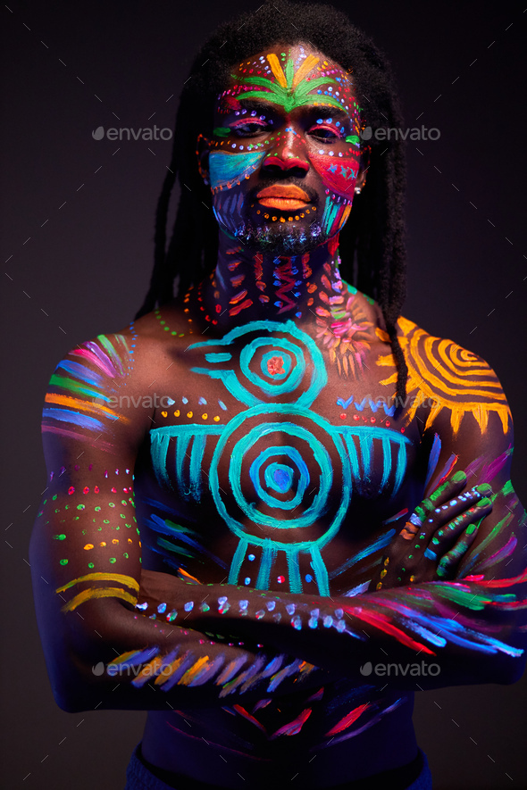 african man painted in fluorescent paint on face and muscular torso ...