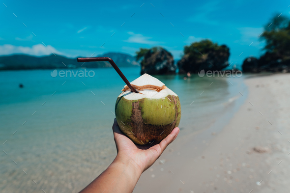 coconut in hand at the beach on a summer day Stock Photo by ArtRachen