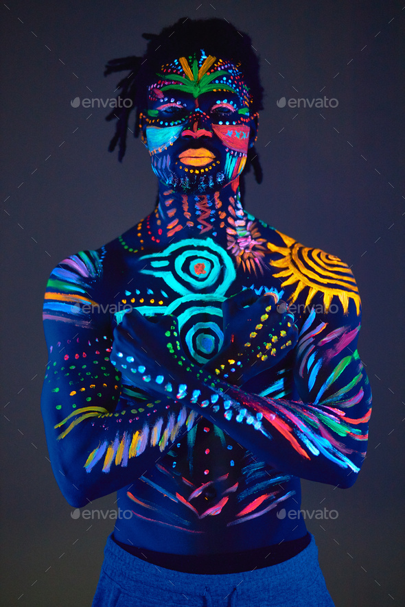 african man painted in fluorescent paint on face and muscular shirtless ...