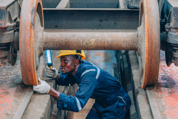 Rail technician inspects train wheels with flashlight for faults and ...