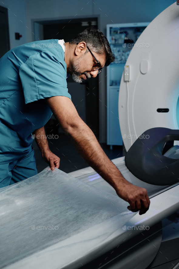 Doctor Preparing CT Scanner Bed For Next Patient Stock Photo by AnnaStills