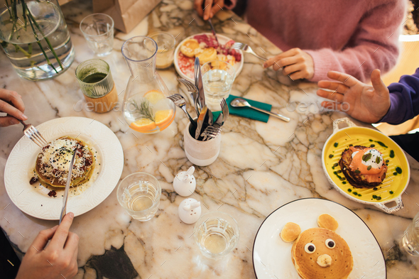 Group of millennial friends having breakfast together in a coffeeshop ...