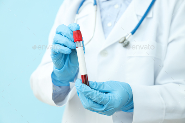 Doctor with test tube with donor blood in hands on blue background ...