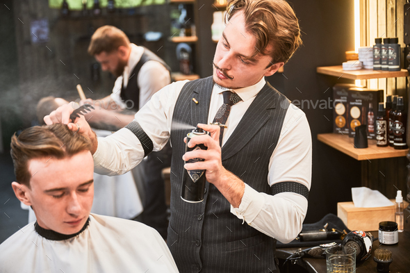Professional barber using hairspray to finish hairstyle. Stock Photo by ...