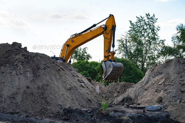 Excavator during earthmoving at open pit on blue sky background ...