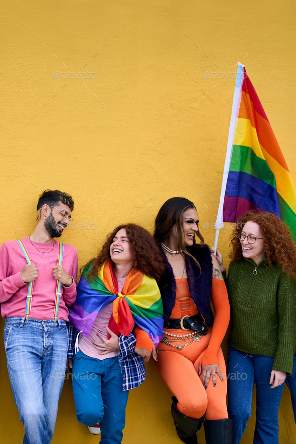 Group of diverse LGBT young people leaning on wall yellow. Smiling ...