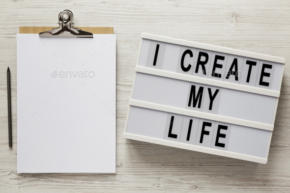 'I create my life' words on a lightbox, clipboard with blank sheet of ...
