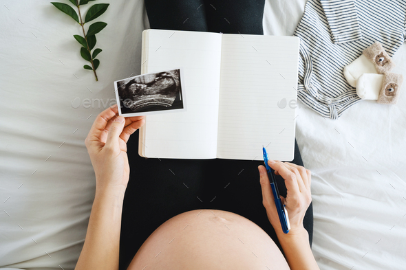 Pregnant woman with blank planner notebook, ultrasound images and ...