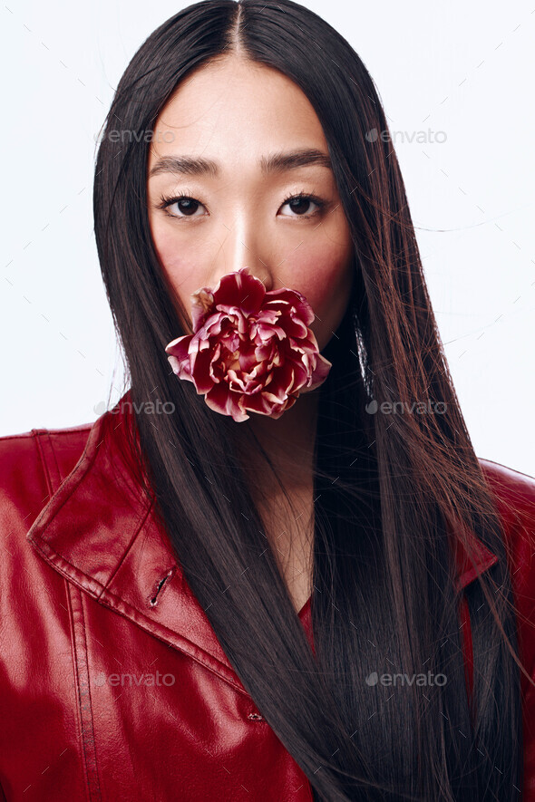 Seductive Asian woman in a red leather jacket holding a flower in her ...