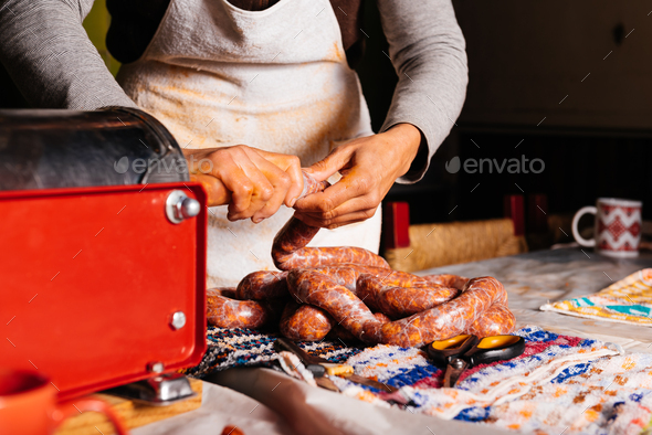 Crop female butcher making chorizo with machine Stock Photo by galdricp