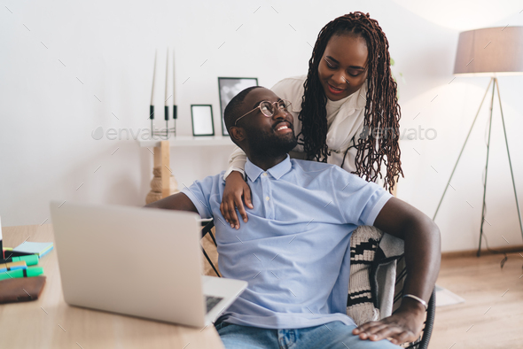 Smiling black woman hugging African American man with laptop Stock ...