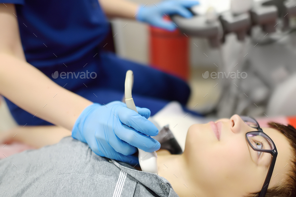 Doctor making ultrasound of the thyroid gland for boy using scanner ...