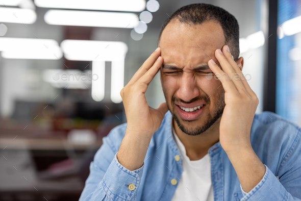 A close-up photo of a Muslim young man sitting in the office behind the ...