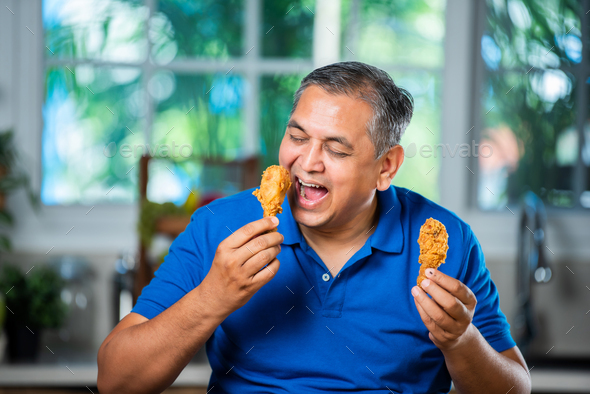 Indian asian mid age handsome man eating chicken leg piece with ...