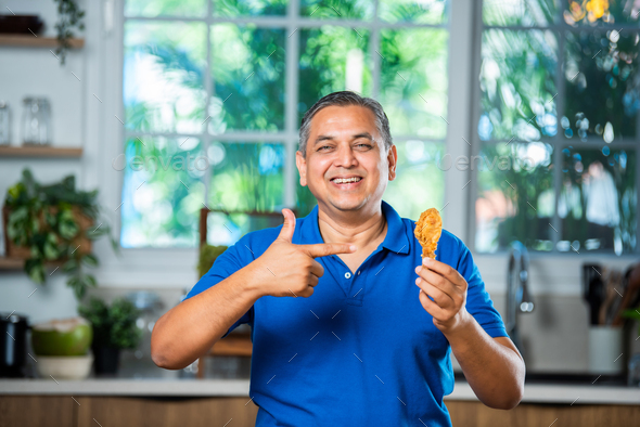 Indian asian mid age handsome man eating chicken leg piece with ...