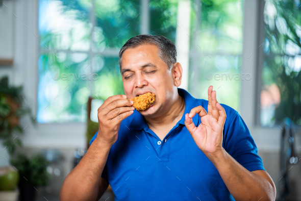Indian asian mid age handsome man eating chicken leg piece with ...