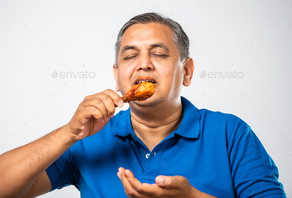 Indian asian mid age handsome man eating chicken leg piece with ...