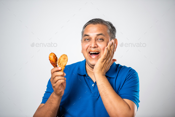 Indian asian mid age handsome man eating chicken leg piece with ...