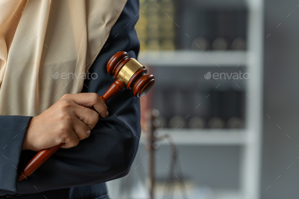 An Asian female Muslim lawyer wearing a hijab stands with her arms ...