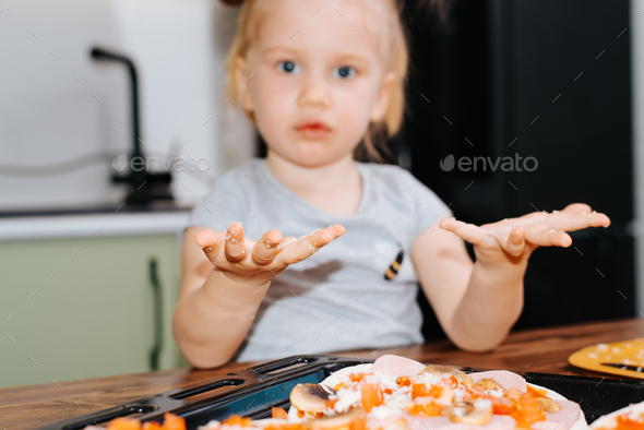 Little girl showing food-stained hands in kitchen, cooking. Selective ...