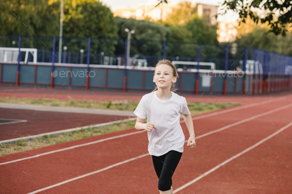 Smiling tween girl runner on a racing track. Stock Photo by ...