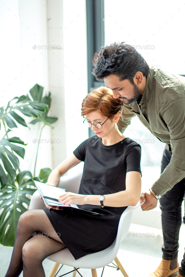 Two business people in discussing information and taking notes as they ...