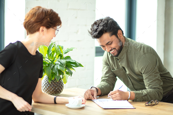 Two business people discuss meeting table with documents and write ...
