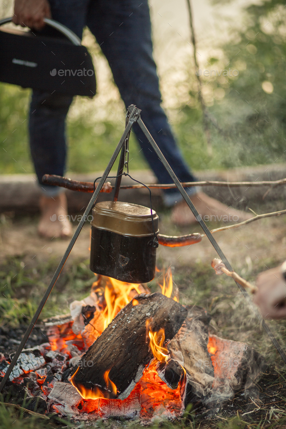 a bucket of water is hanging over the campfire Stock Photo by ...