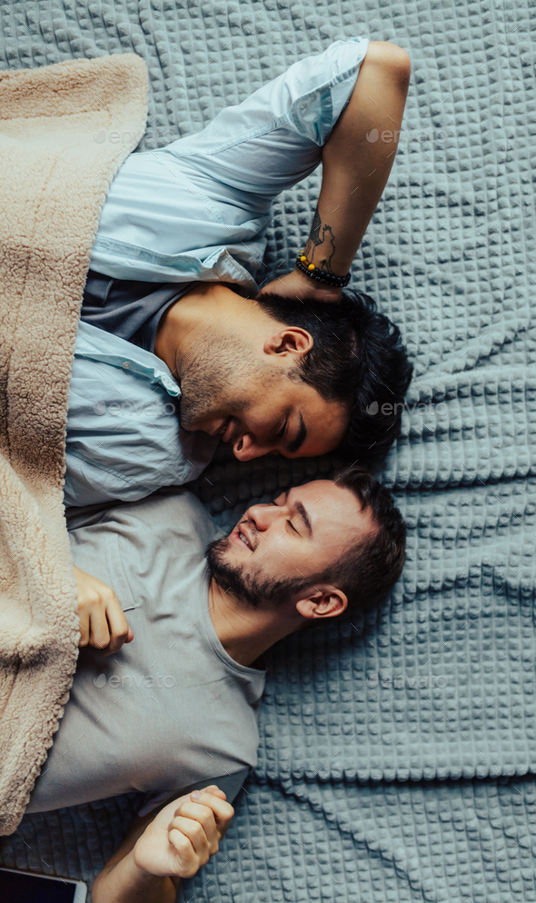 Handsome sleepy man with bristle kissing good night male partner lying ...