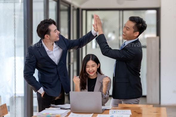 Excited business team giving high-fives over successful project at the ...