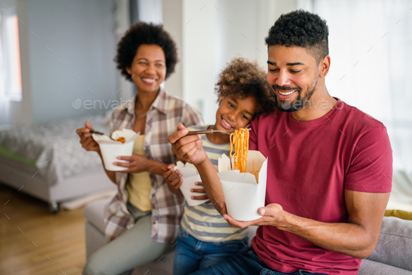 Happy african family eating at living room and enjoying time together ...