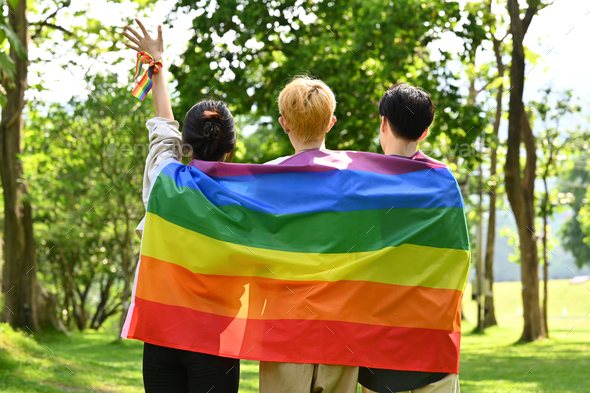Group of young people holding pride rainbow flag, supporting LGBTQ ...