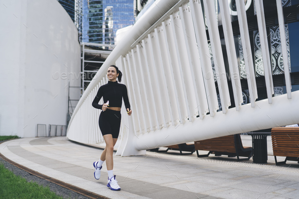 Slim woman in sportswear jogging on walkway Stock Photo by GaudiLab