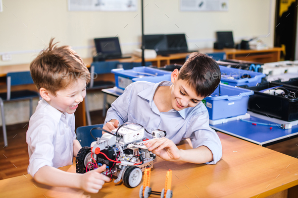 Two brothers kids playing with robot toy at school robotics class ...