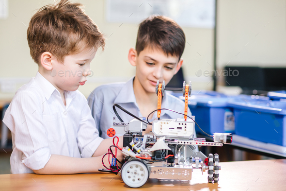 Two brothers kids playing with robot toy at school robotics class ...