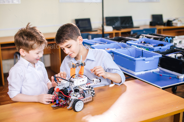 Two brothers kids playing with robot toy at school robotics class ...