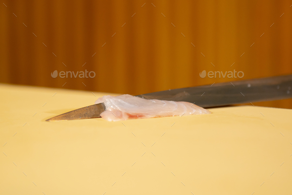 close up in a Japanese restaurant chef in a blue uniform cuts fish for ...