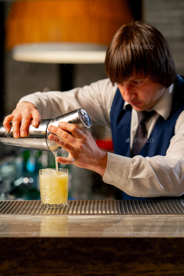 in a Japanese restaurant behind the bar bartender pours a cocktail from ...