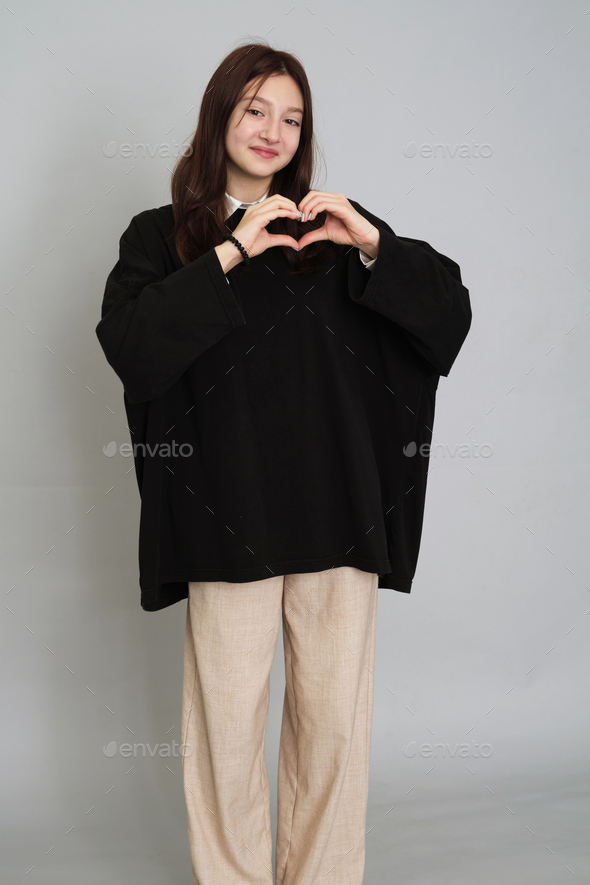 Joyful lady forms a heart with fingers, conveying feelings of affection ...
