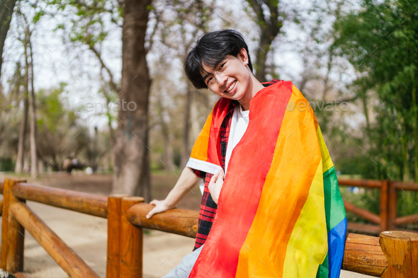 Young Chinese Man Expressing LGBTQ Pride with Multicolor Flag in Park ...