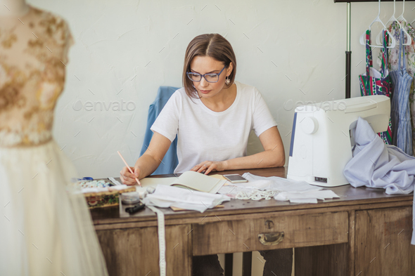 Fashion designer at work. Talanted dressmaker drawing sketch at her ...