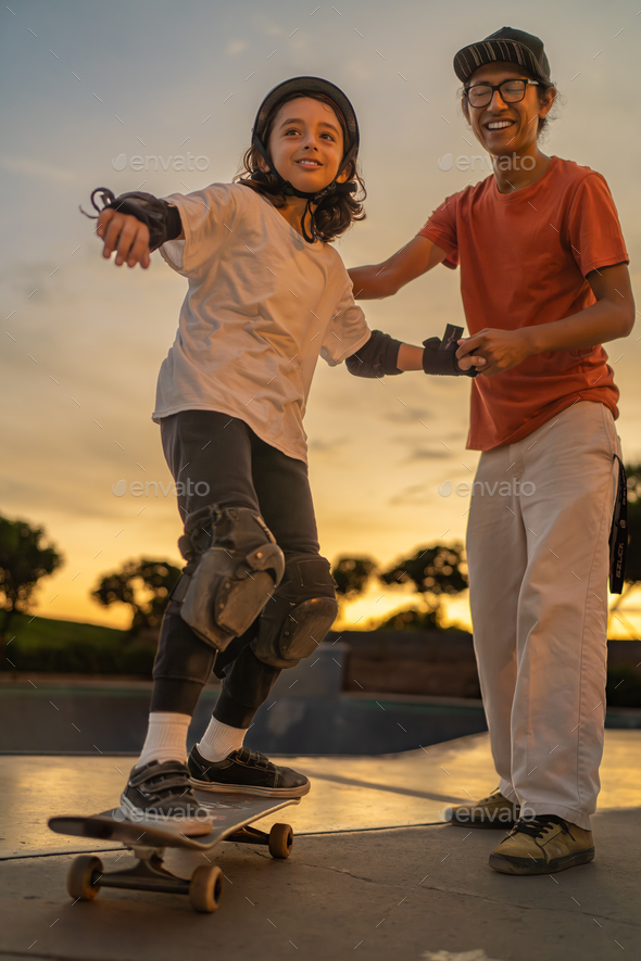 Boy in his first skateboarding lesson with his coach at the skate park ...