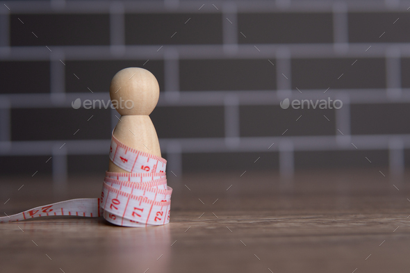 Wooden doll and measuring tape. Stock Photo by mohdizzuanbinroslan