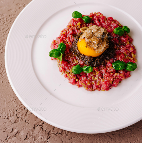 Gourmet tartare with quail egg and truffle Stock Photo by AntAlexStudio