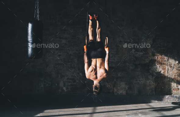 Strong anonymous man doing exercise upside down on rings in gym Stock ...