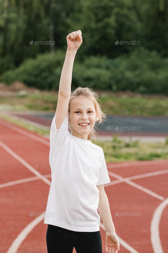 Happy smiling child girl raises her hand up in victory on the running ...