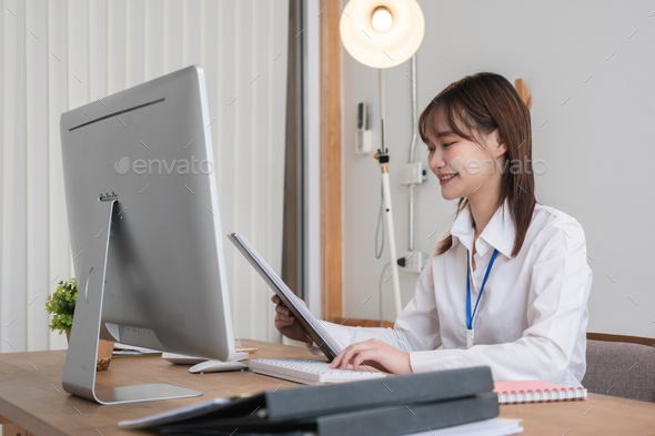 Cheerful business lady working on computer in office, Asian happy ...