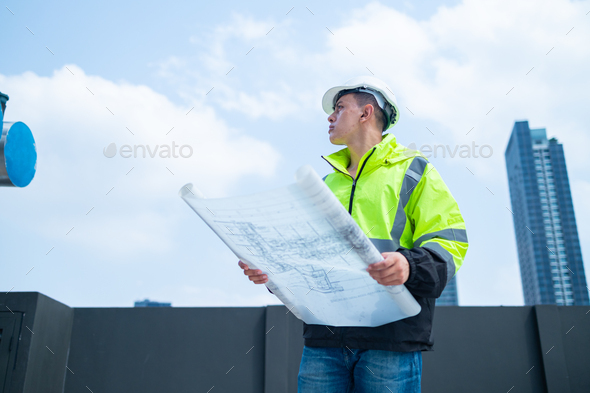 Construction Engineer Evaluating Blueprints on Rooftop Stock Photo by ...